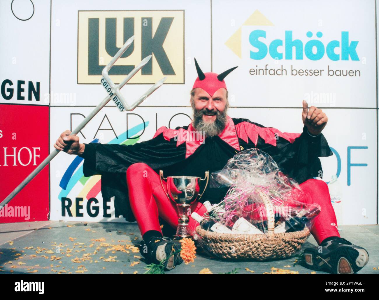 Tour devil Dieter (Didi) Senft sits in front of a billboard with a ...