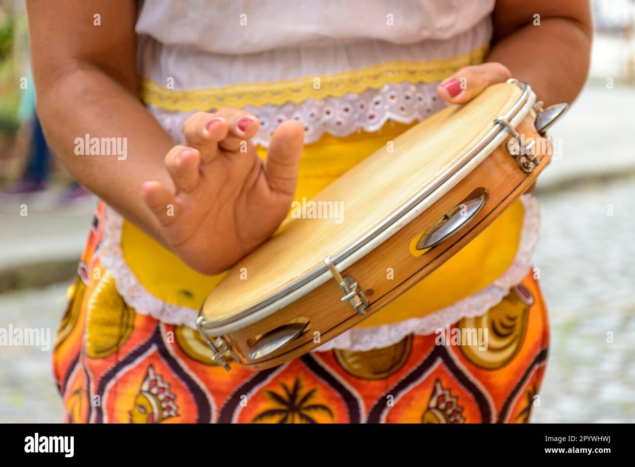 Young woman in colorful clothes playing the tambourine during a samba ...