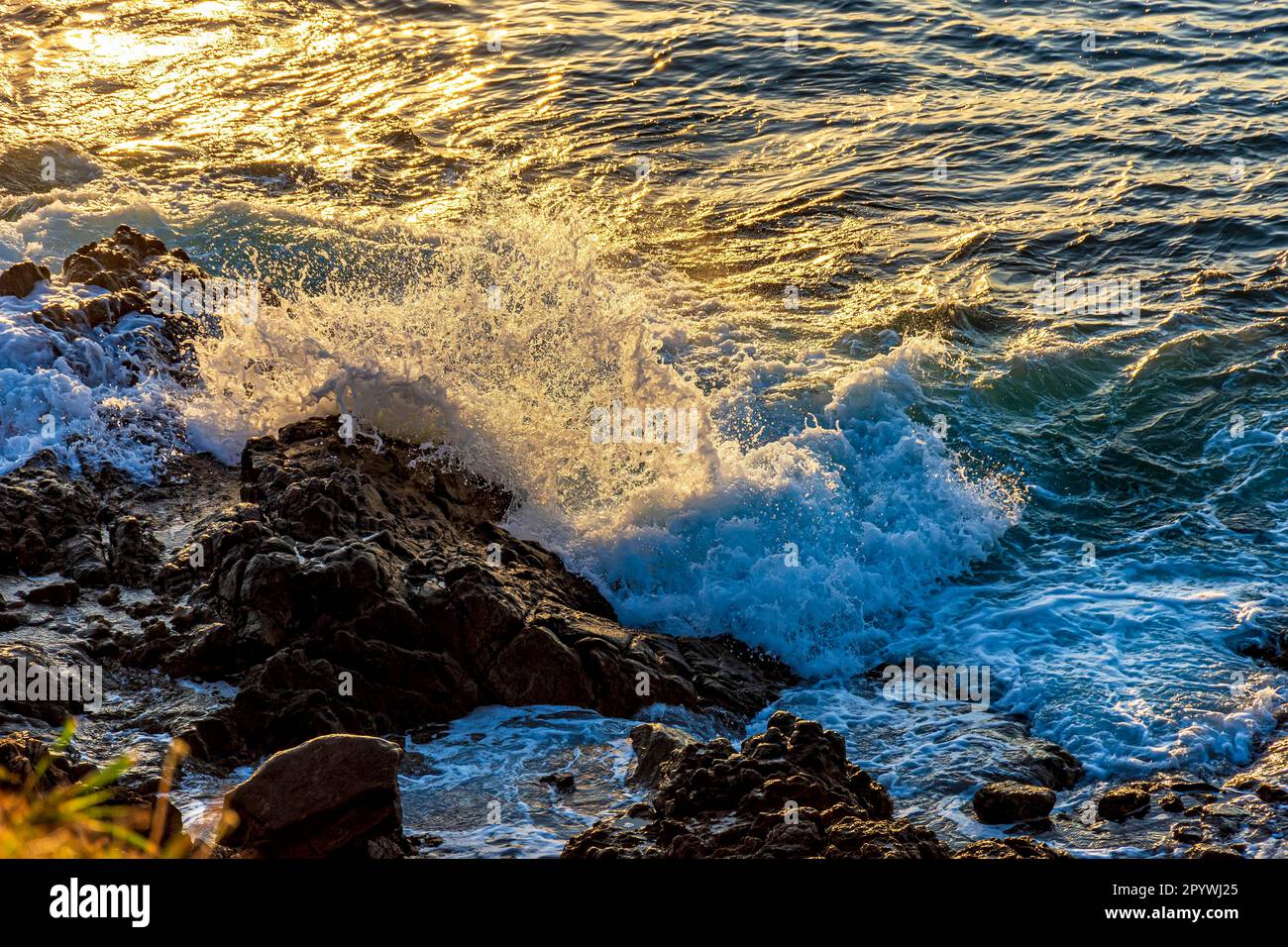 Water and sea foam splashing with the shock of waves against the rocks ...