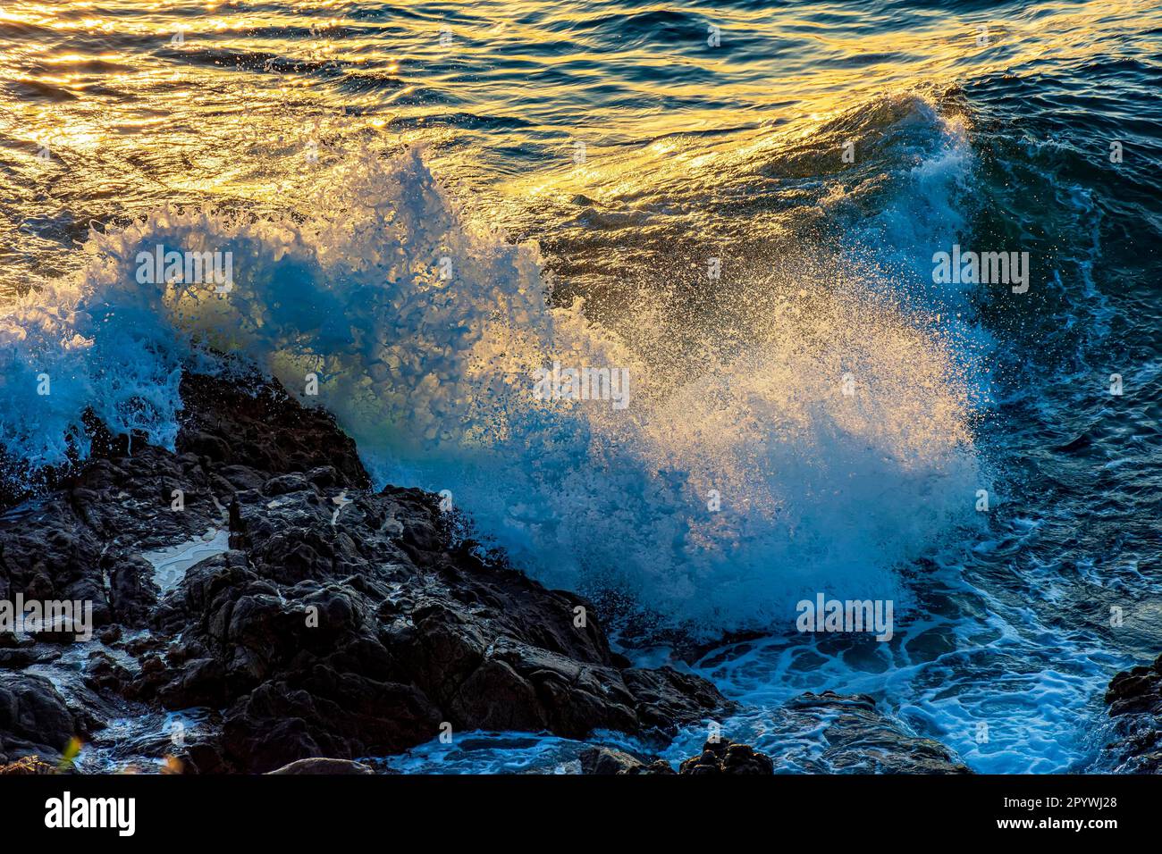 Water and sea foam splashing with the shock of waves against the rocks ...