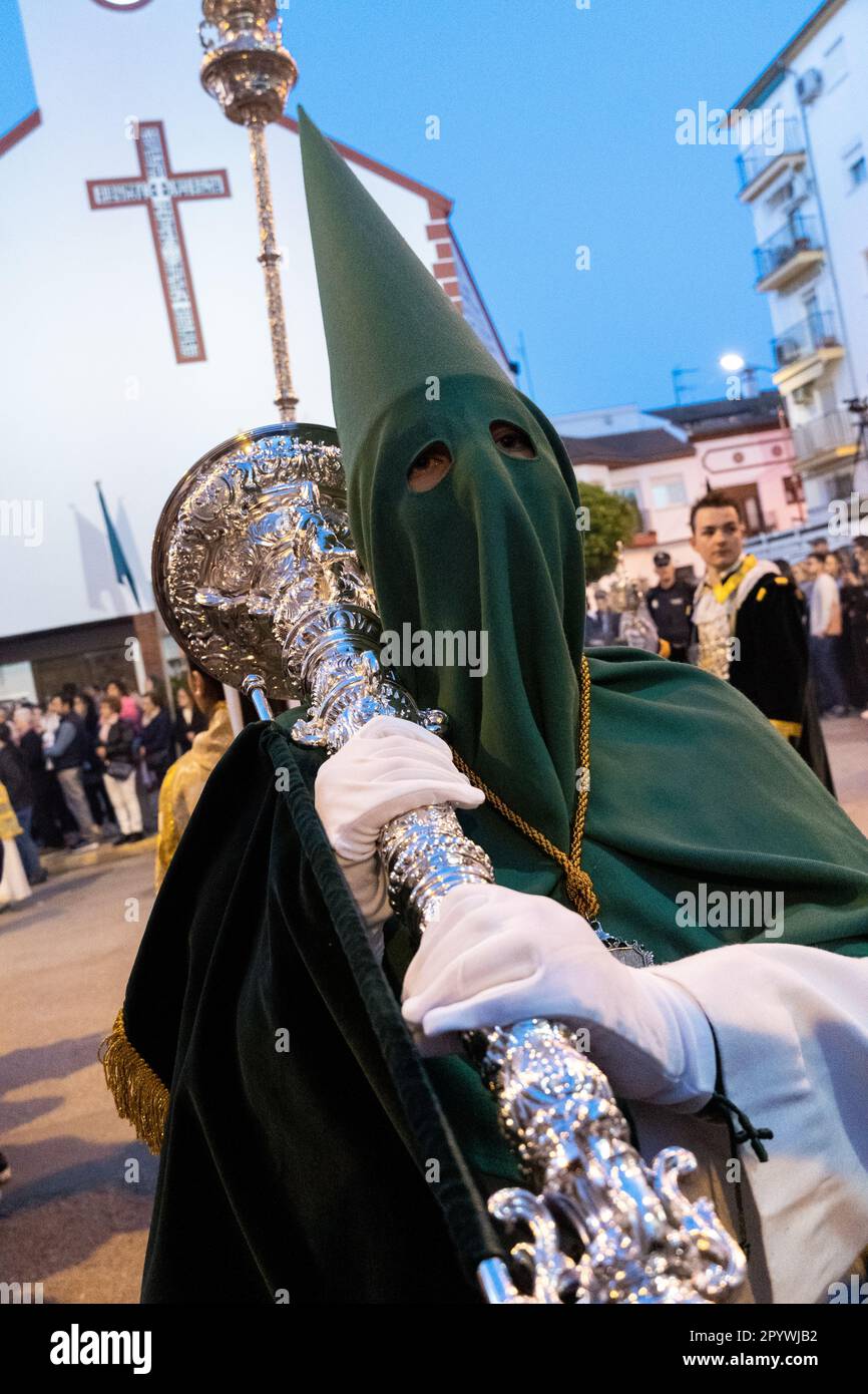 A Cofradia wearing a green cone shaped hood walks in a procession ...