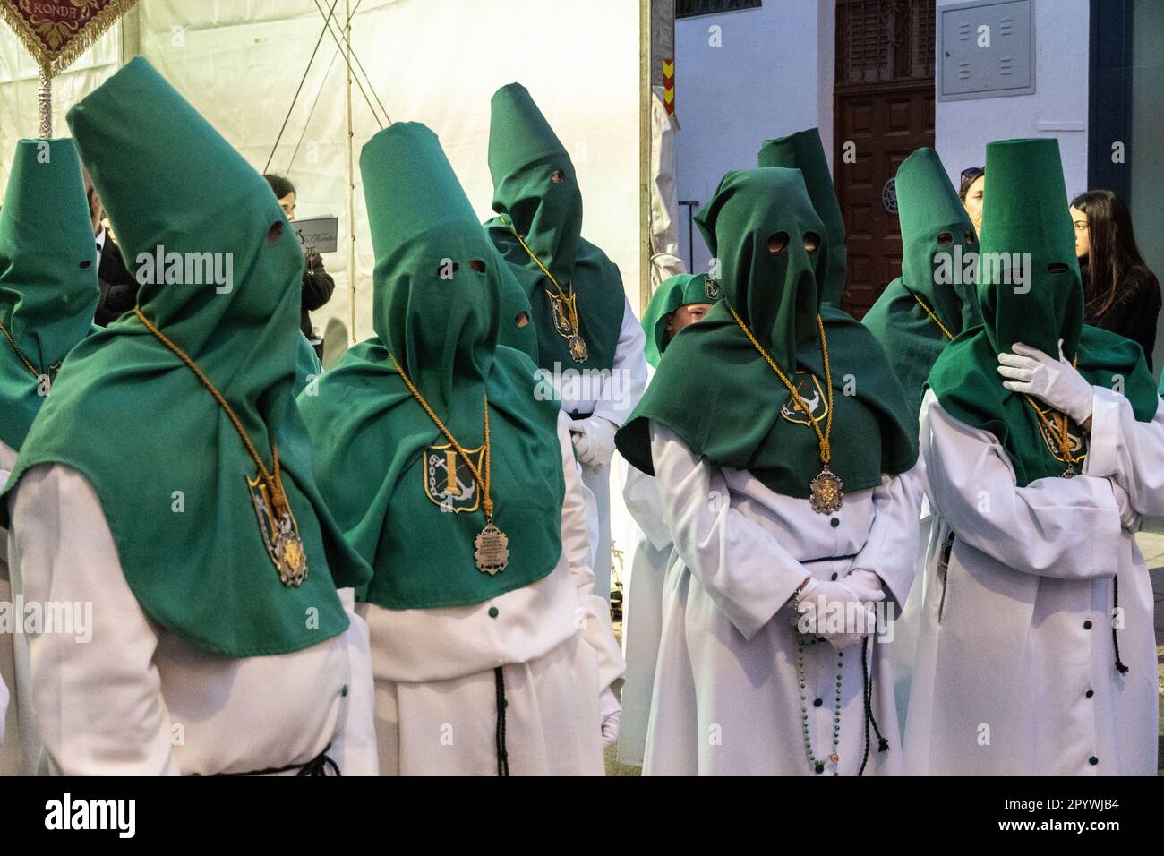 Cofradias wearing green hoods prepare for a procession during Holy Week ...