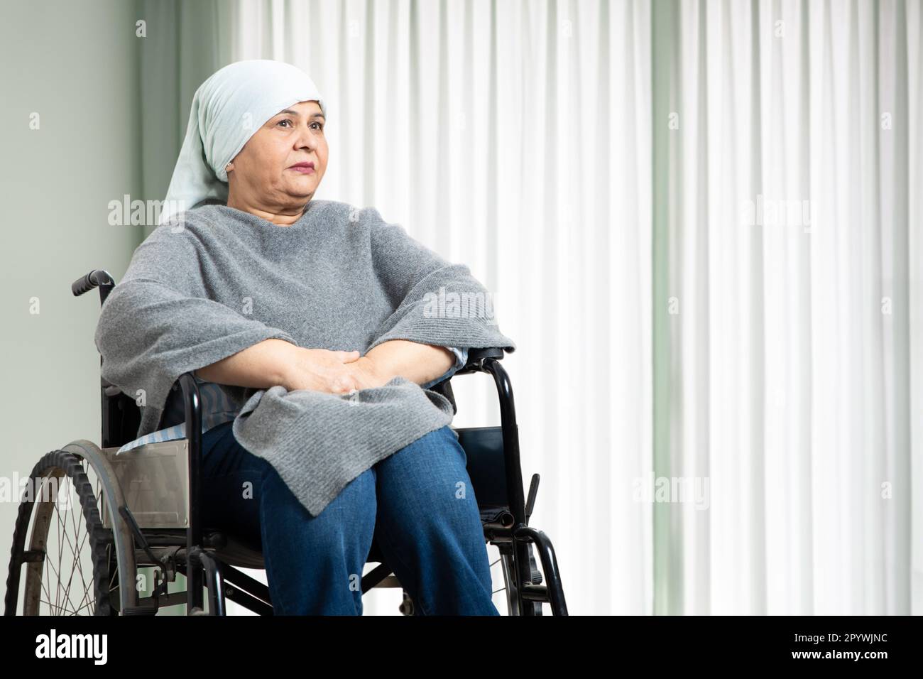 Senior indian woman cancer patient sitting on a wheelchair alone ...