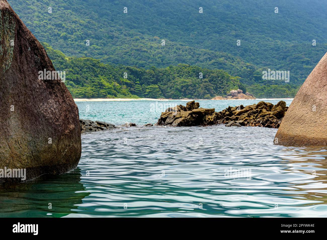 Beach and tropical forest in Trindade, Paraty seen through the rocks ...