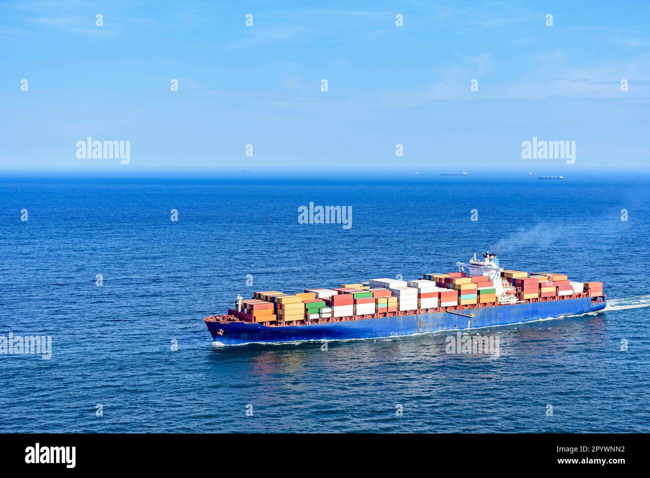 Cargo ship carrying several containers on the waters of the blue sea of ...