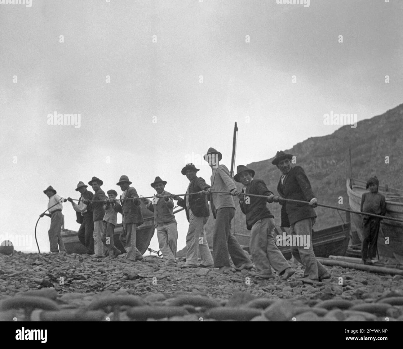 Men pull a boat out of the sea with a rope Stock Photo - Alamy