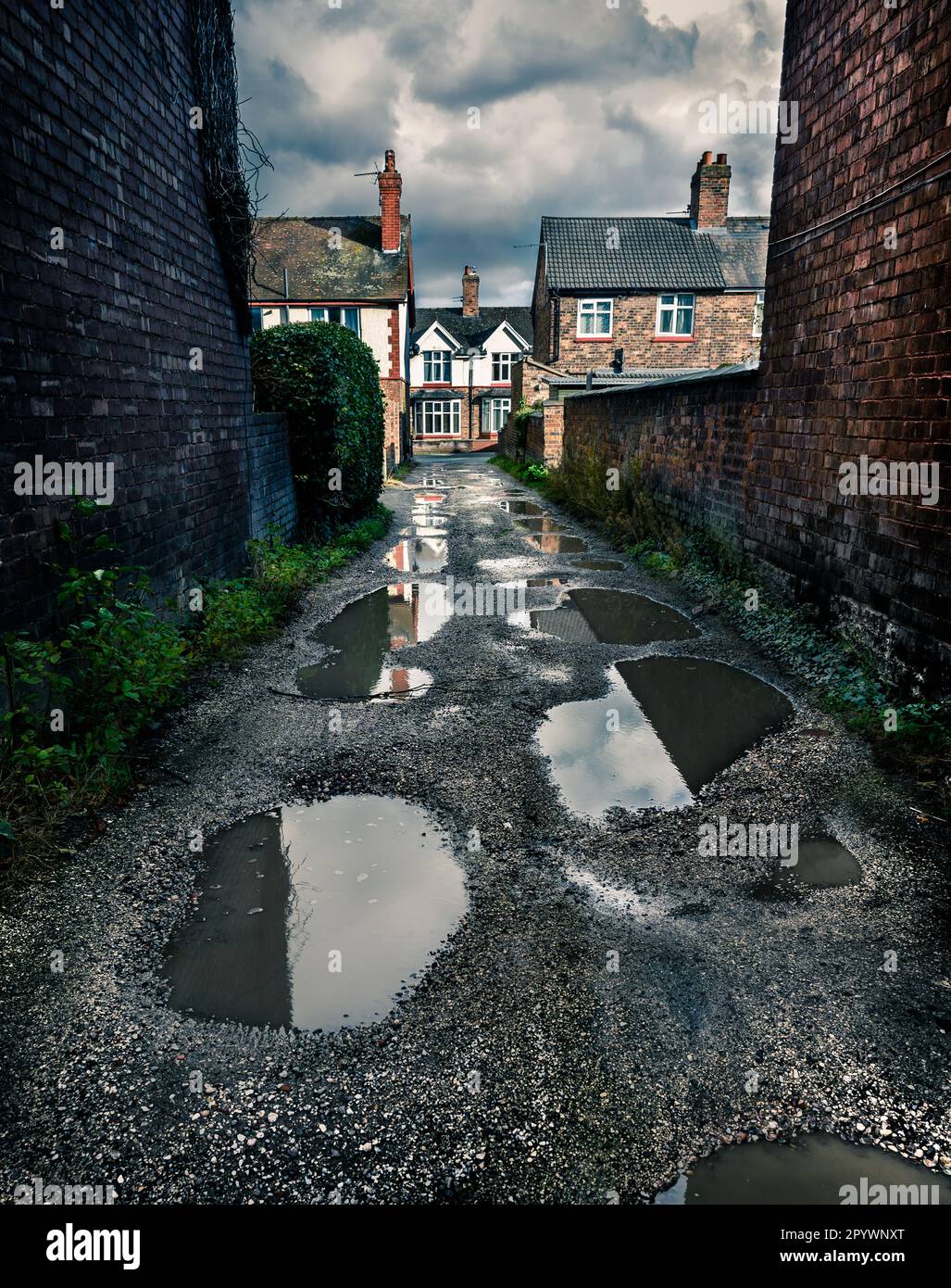 Pot hole puddles along an alleyway in a terraced house street Stock ...