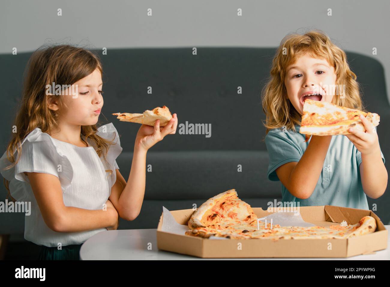 Hungry children eating pizza. Excited kids eating pizza Stock Photo - Alamy