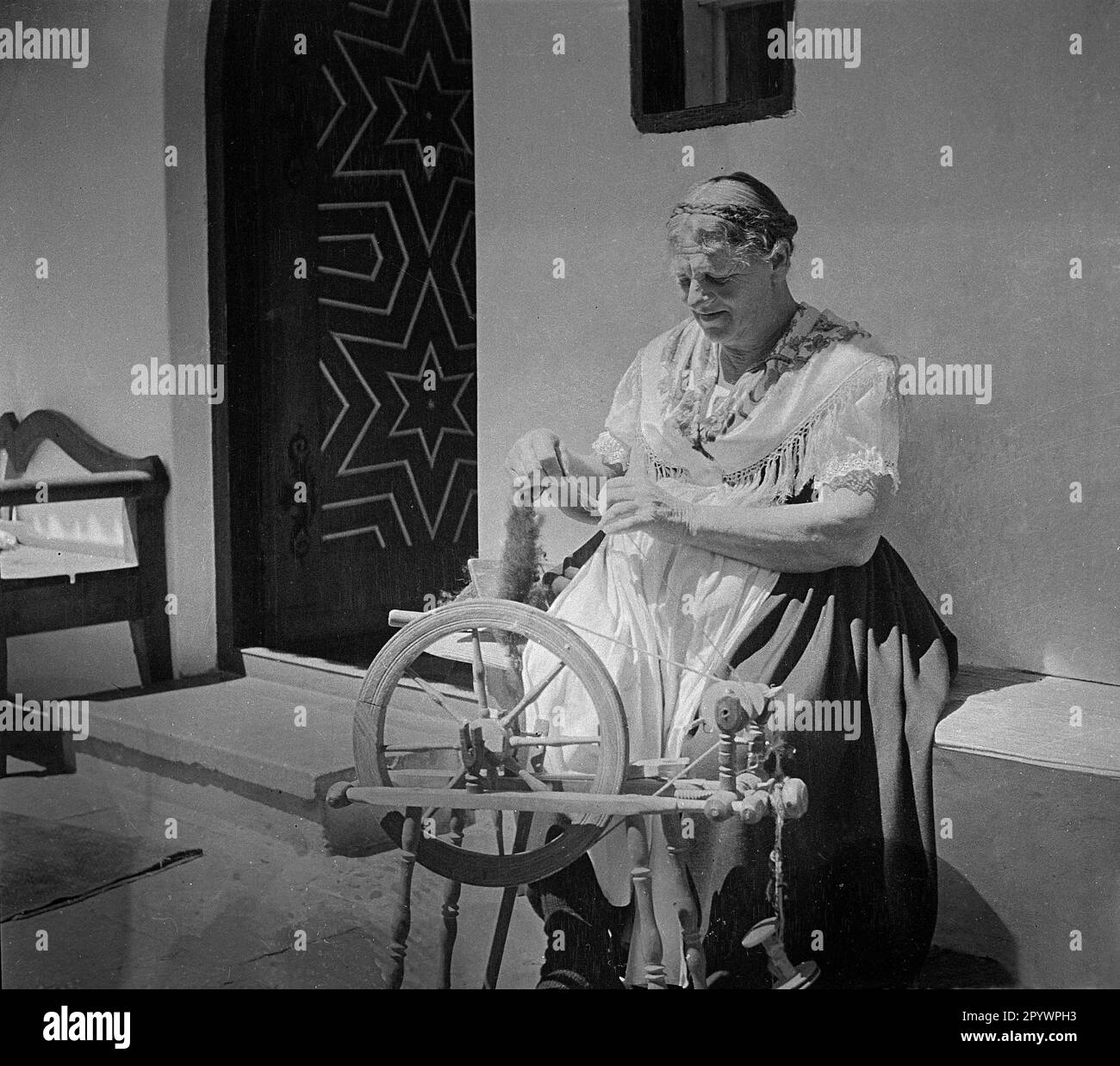 Woman is spinning yarn at the spinning wheel. Undated photo from around ...