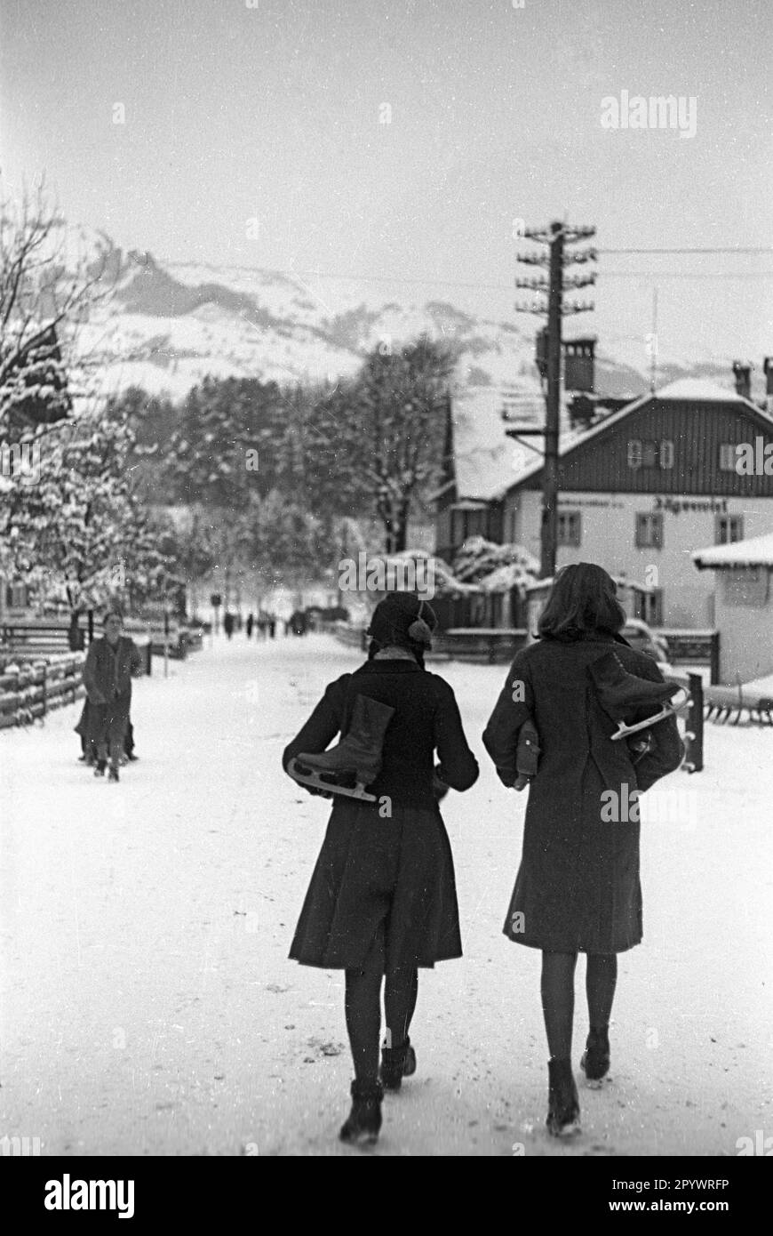 Two young women are walking through St. Johann. Their skates are hung ...