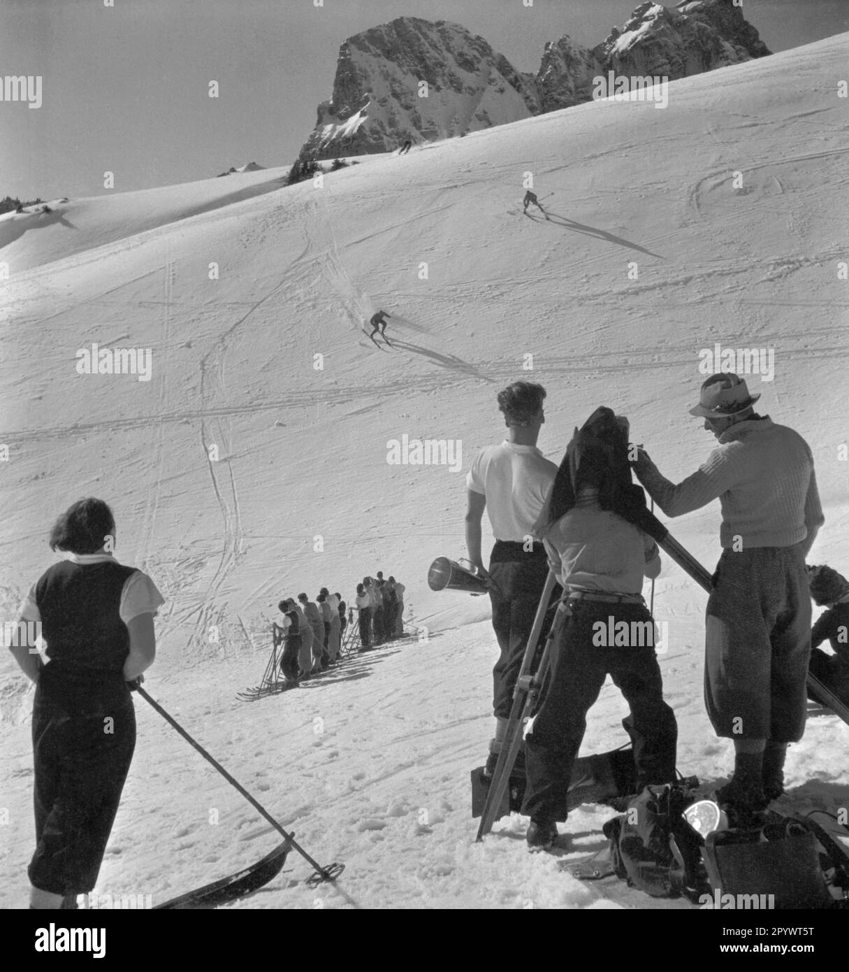 Two skiers descend a slope near Garmisch. They are filmed by a camera ...