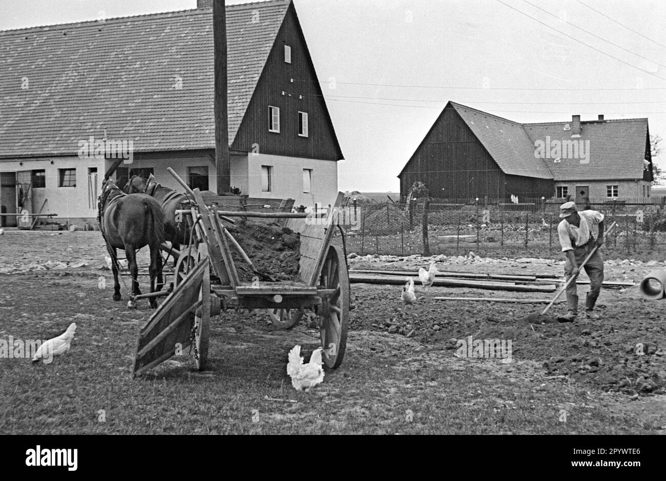 A farmer digs up his field in front of his yard in the new farming ...