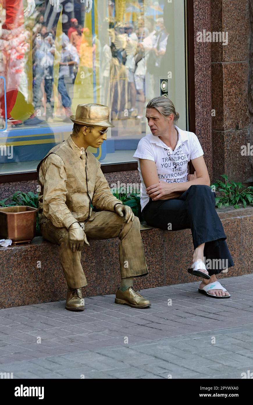 An unidentified passerby chats with an unidentified busking mime ...