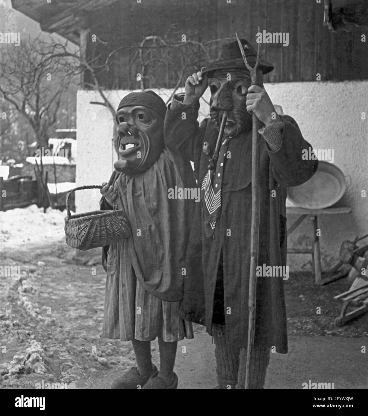 Two people with oversized wooden masks in front of their faces standing ...