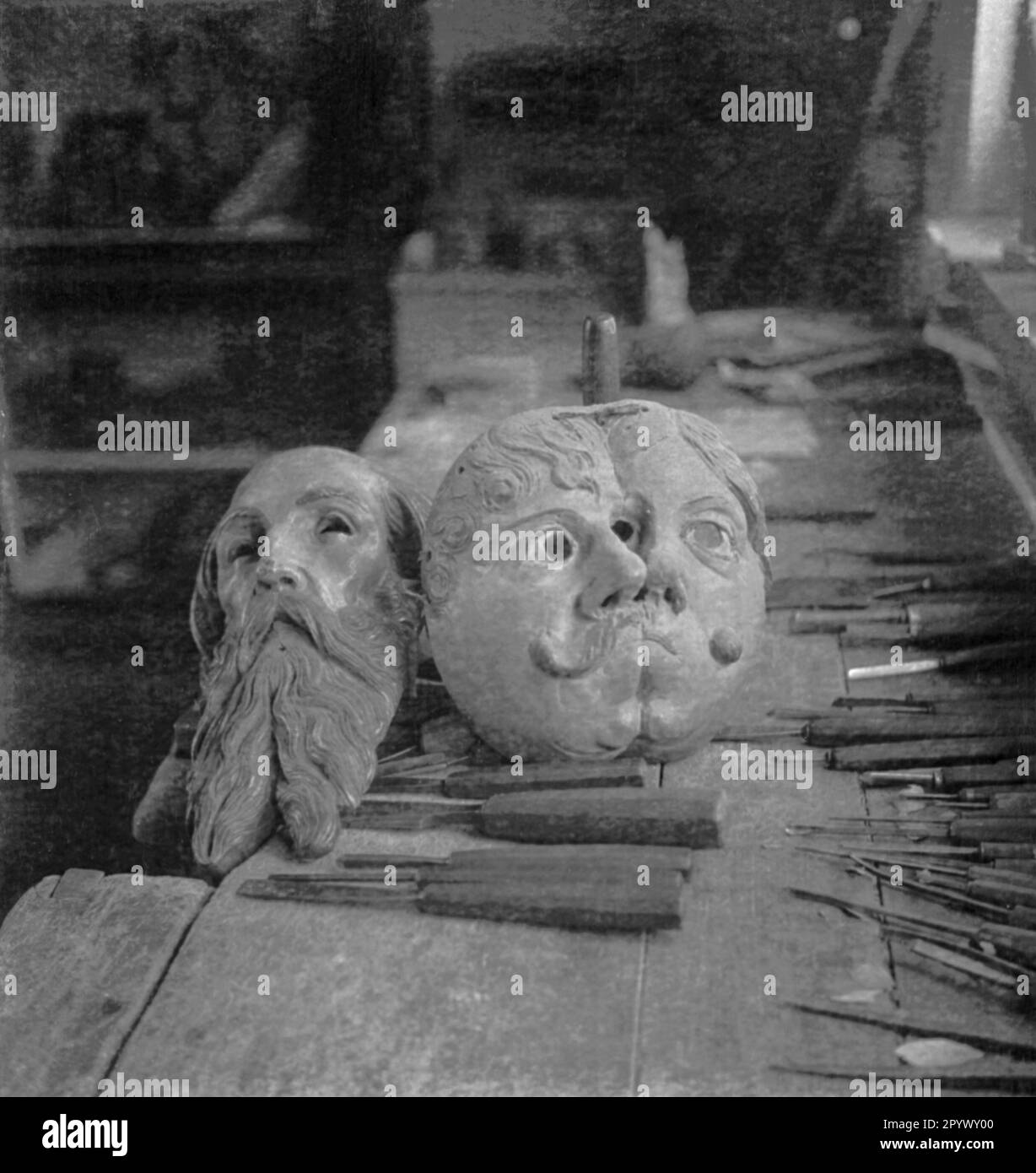 Hand-carved wooden masks on a workbench in a workshop in Upper Bavaria ...