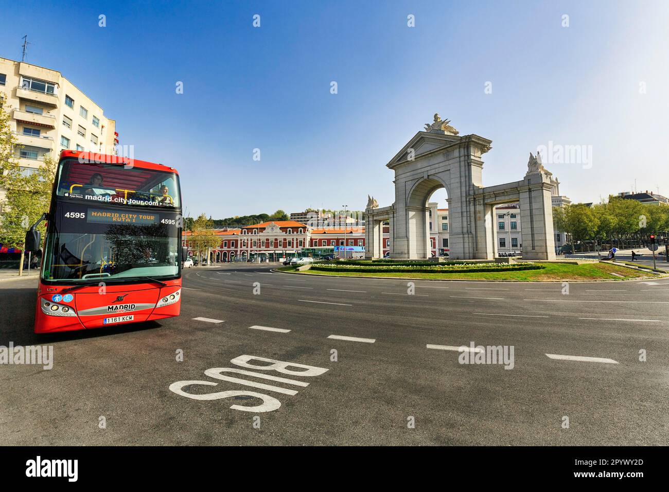 Monumental gate Puerta de San Vicente in a roundabout, red double ...