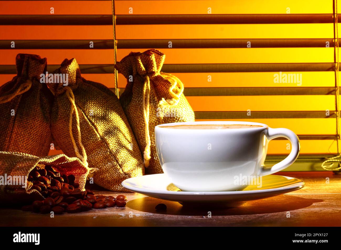 Coffee cup filled with coffee set against a kitchen window blind with ...