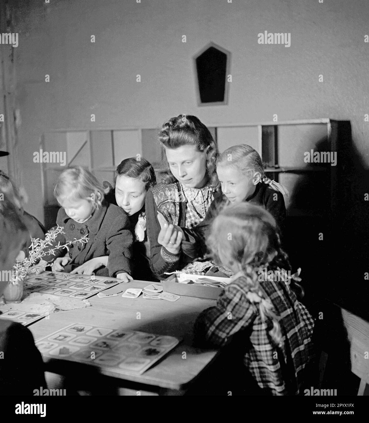 "A mother plays a table game with her children. It is probably a kind ...