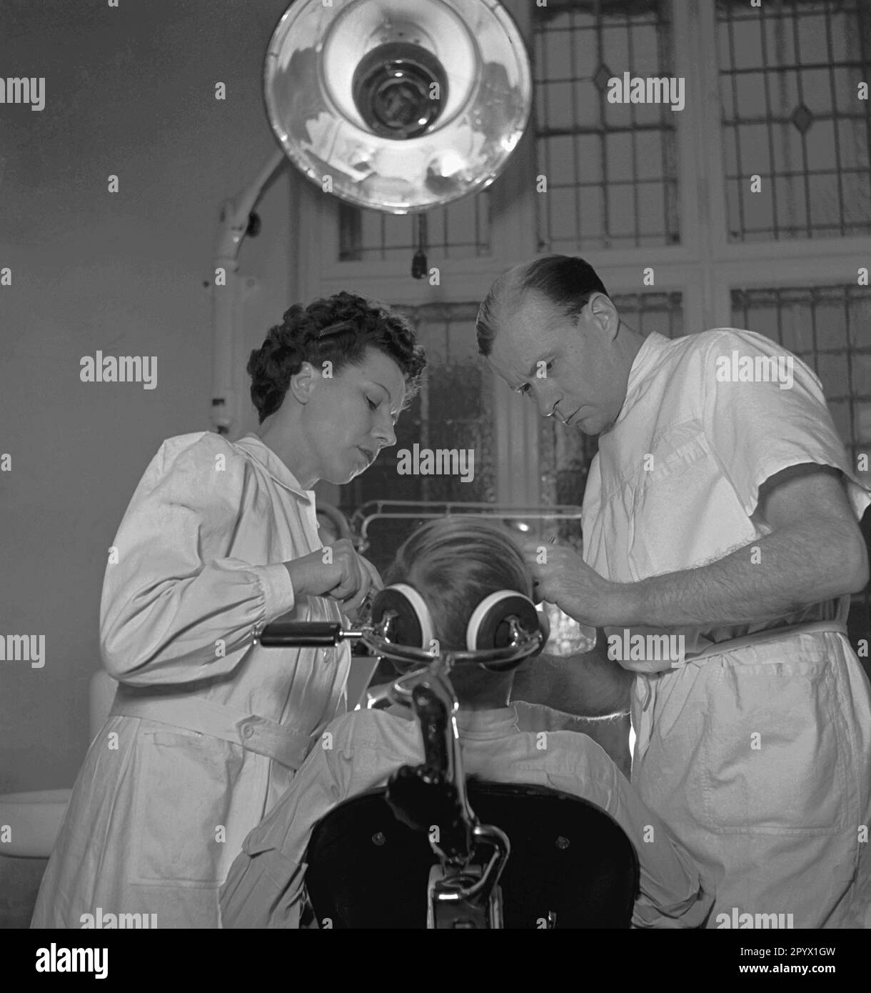 "Dentist Freese treats a patient. He is supported by a doctor. Scene ...