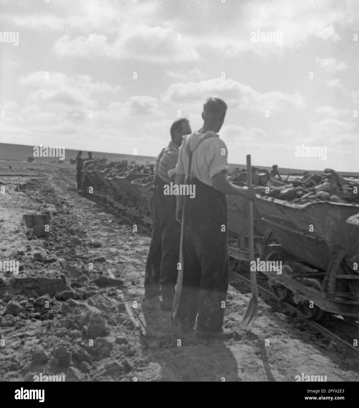 Workers load the freight trolley with silt from the mudflats. This ...