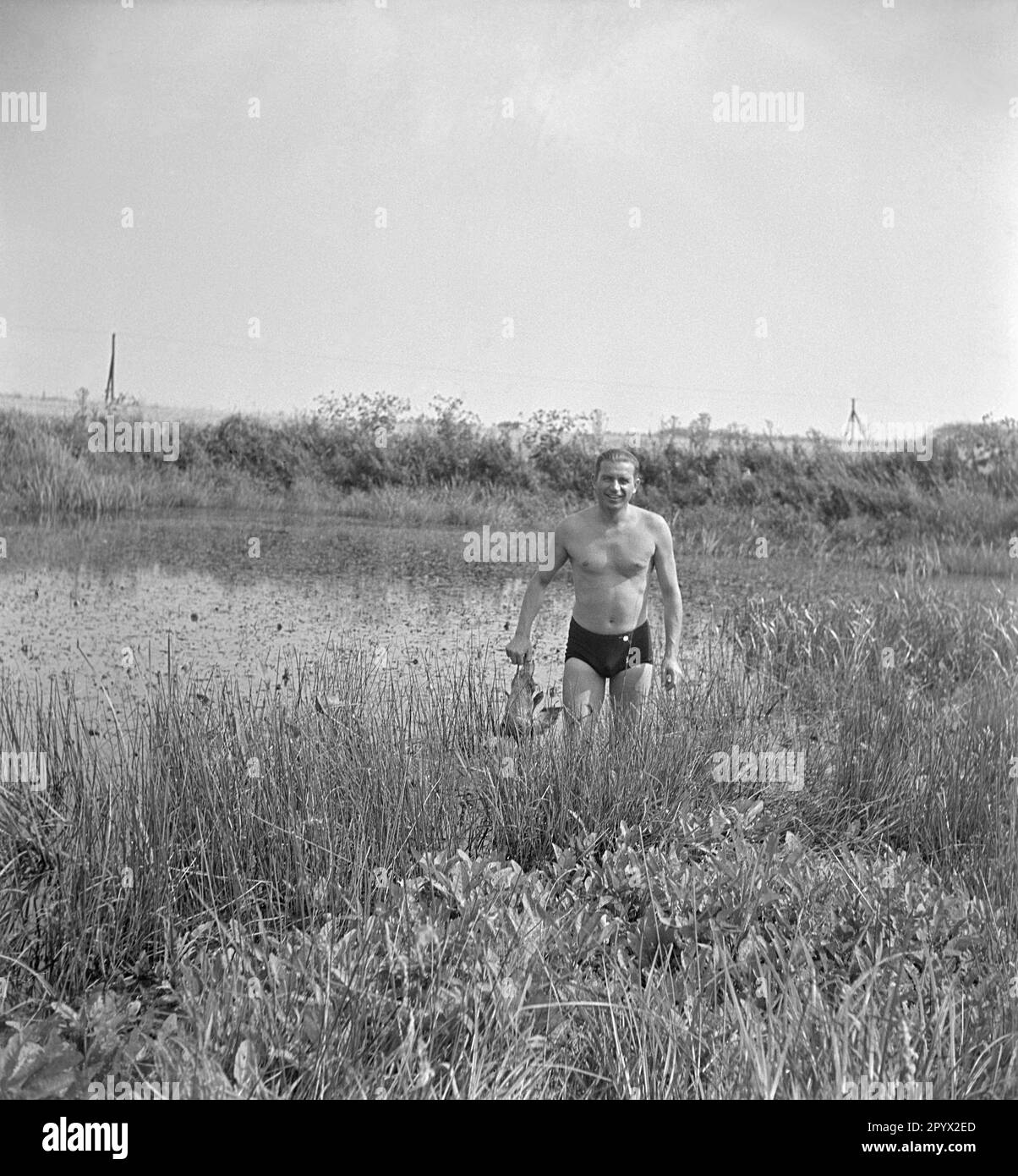 A man in swimming trunks returns successfully from the hunt. In one ...