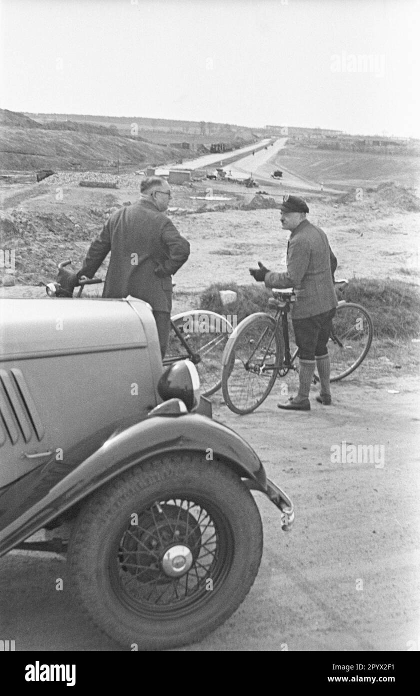 Cyclists talking. In the background, building work on the highway Stock ...