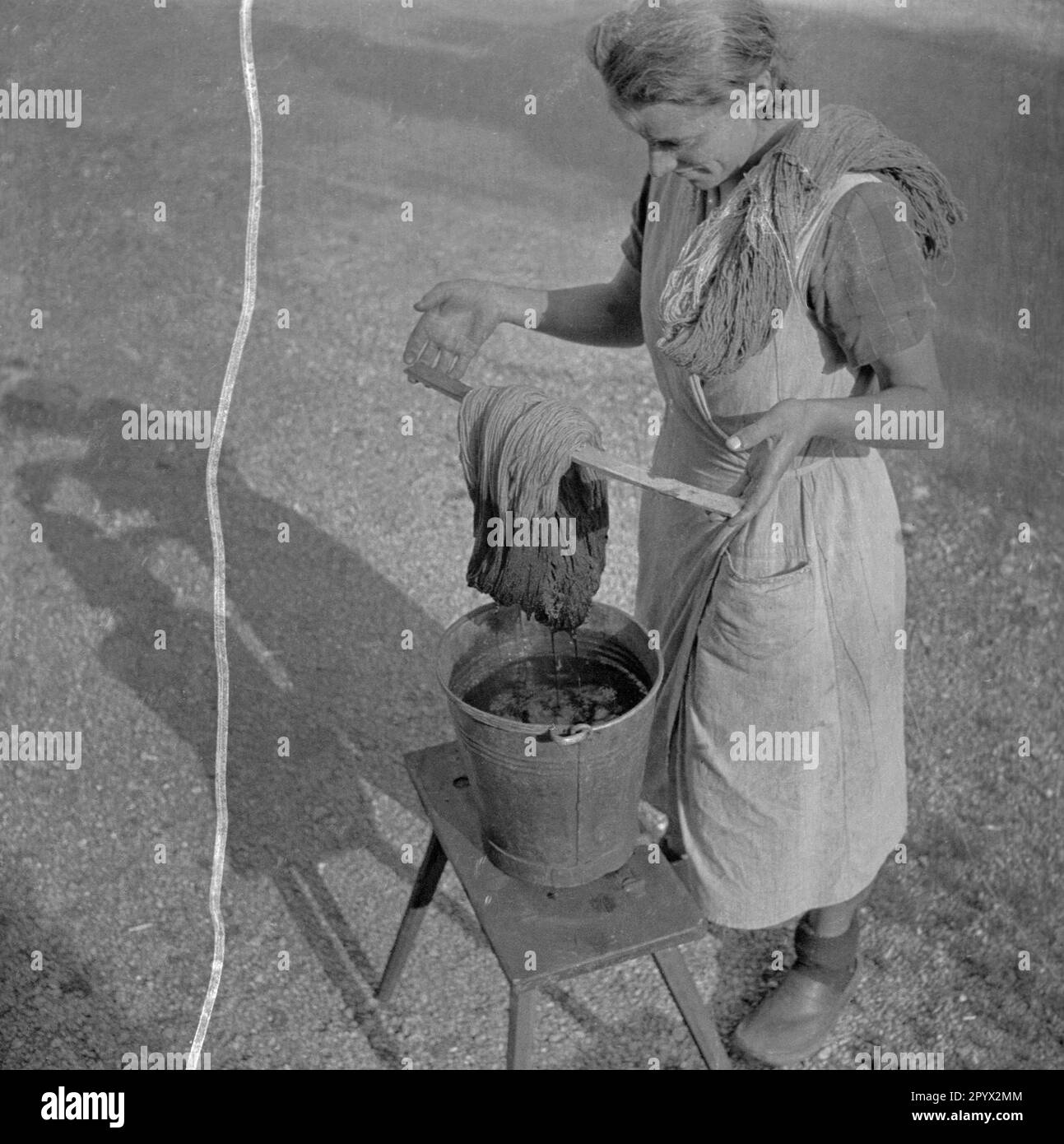 A woman is dyeing the yarn in a bucket Stock Photo - Alamy