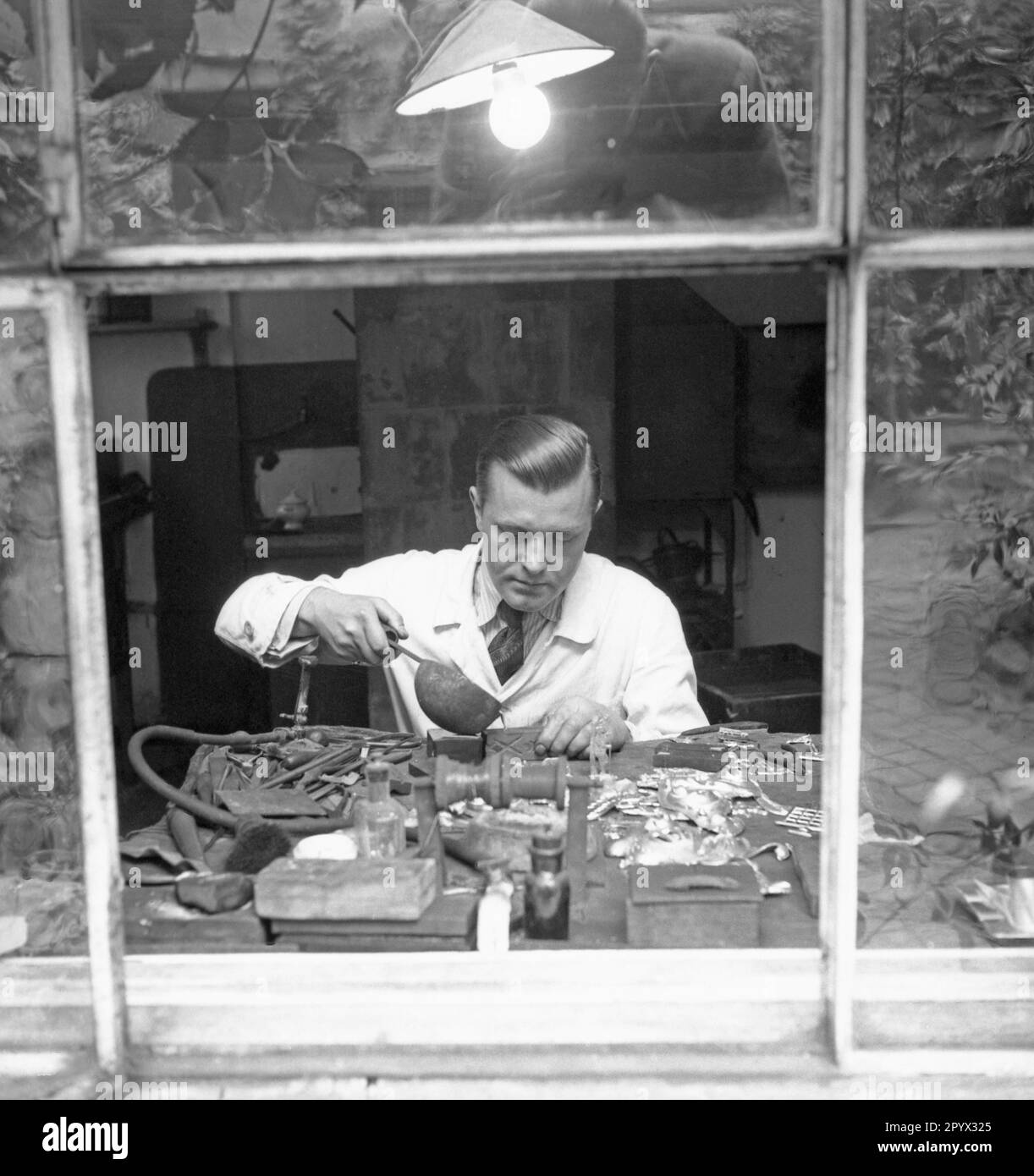 A craftsman pours metal into a crest shape Stock Photo - Alamy