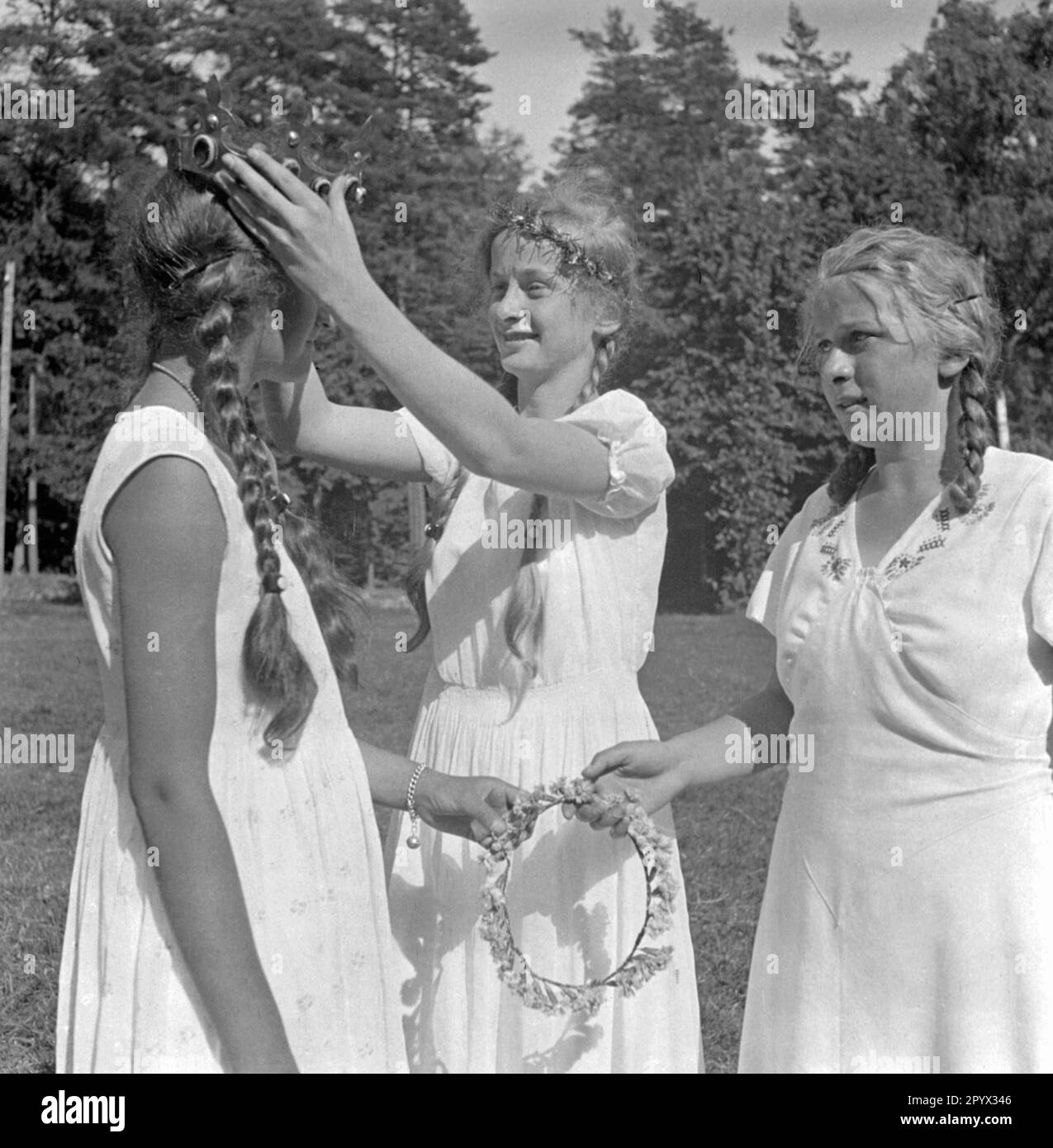 A girl is crowned by two others in Plau in Mecklenburg. All three wear ...