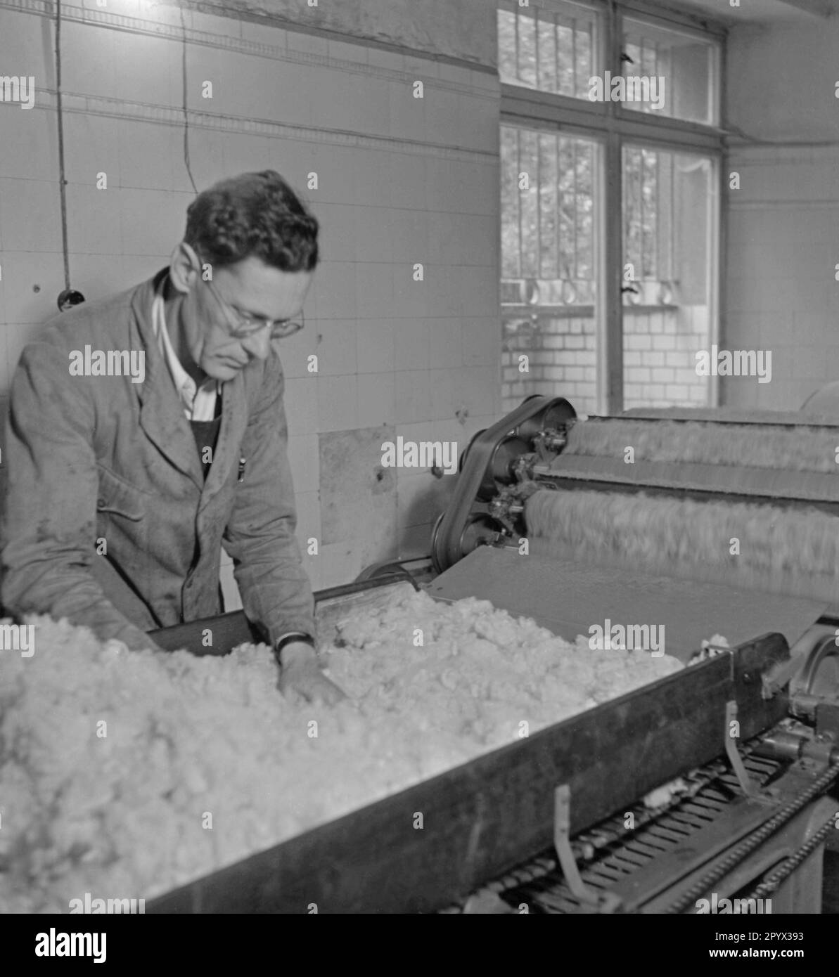A man examines wool in a Berlin weaving mill. Undated photo Stock Photo ...