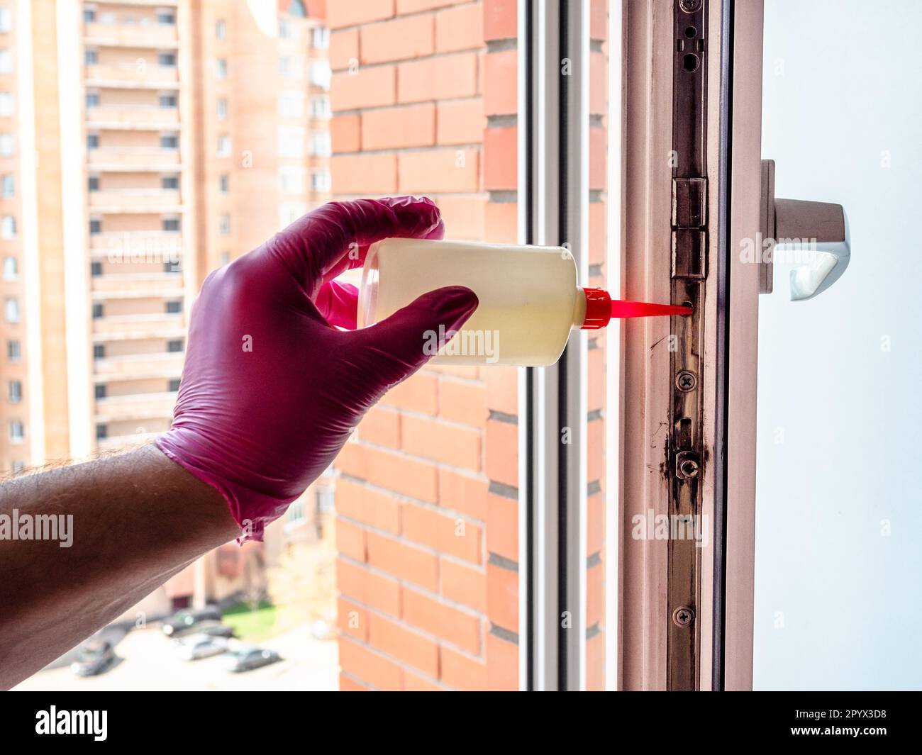 hand in pink glove lubricates mechanism of plastic window frame in ...