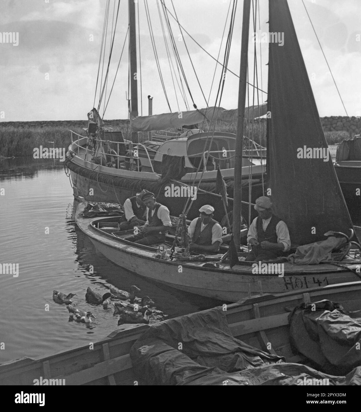 Men work on a small sailboat in the harbor of the Baltic Sea island of ...