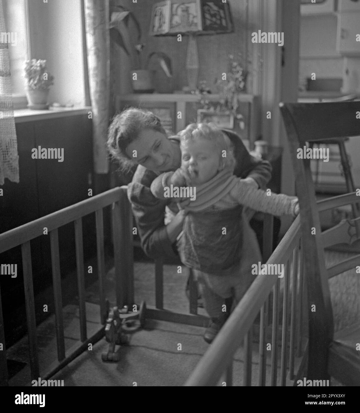 Undated photo of a grandmother playing with her grandchild in a playpen ...
