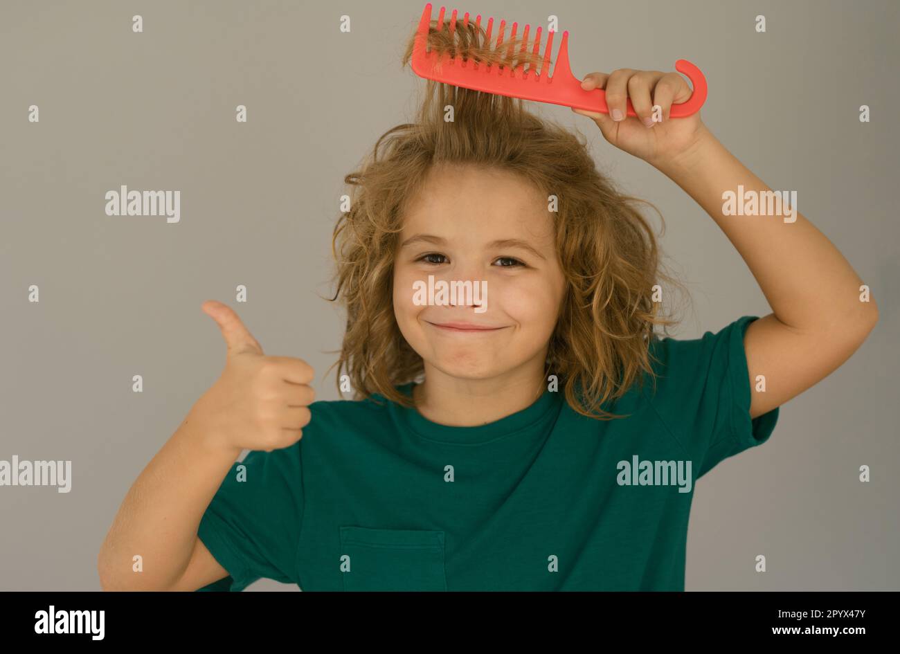 Boy brushes his hair. Cute child with comb. Blonde kid combs unruly ...