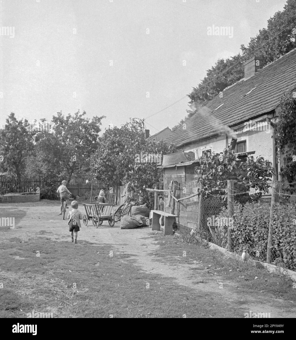 Photo of a group of children playing in front of a farm building in the ...