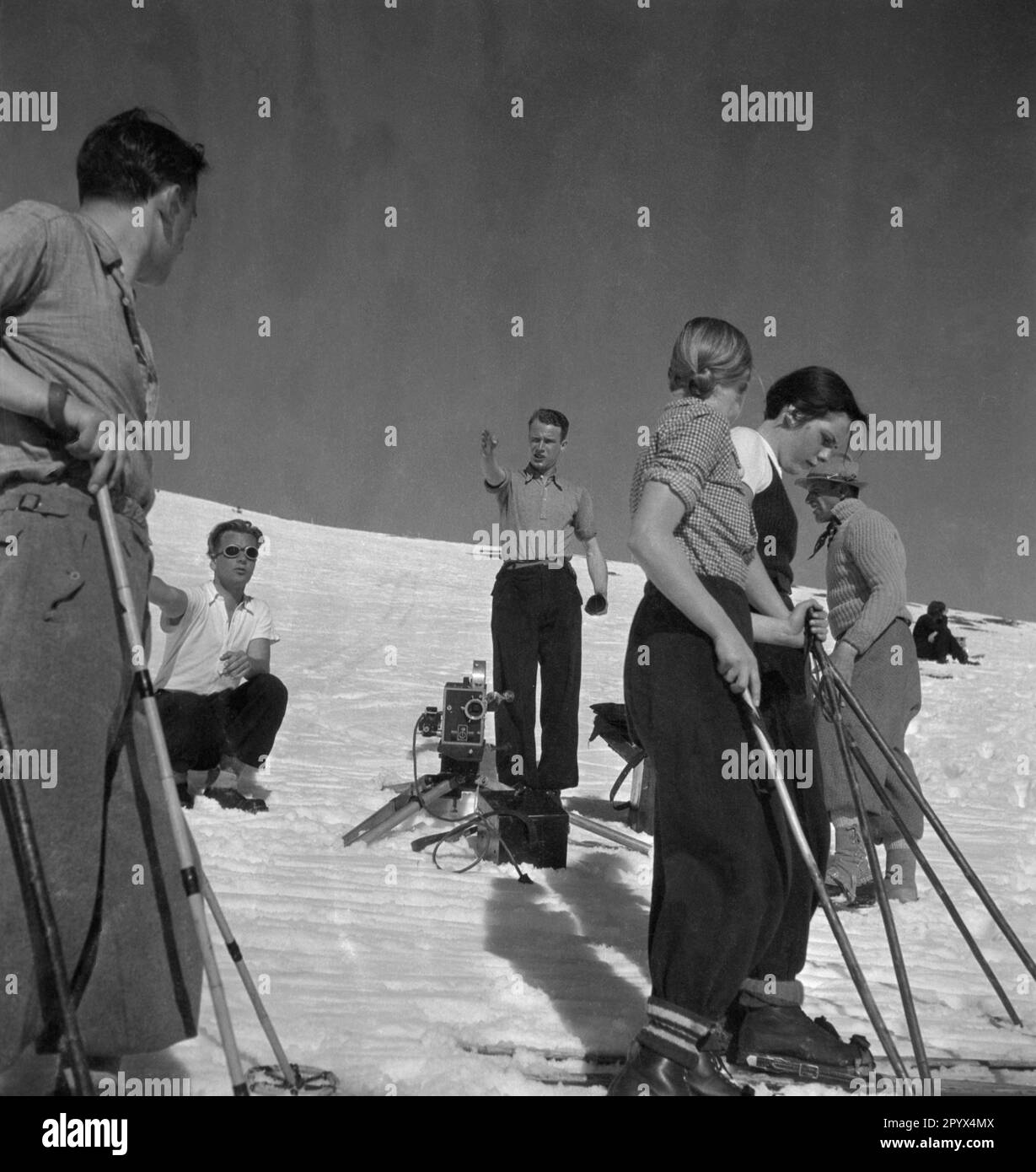 "A cameraman gives instructions to a group of skiers on a high alpine ...