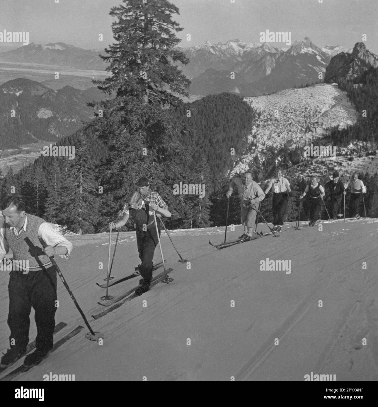 "View of a group of skiers ascending a high alpine pasture in a ...