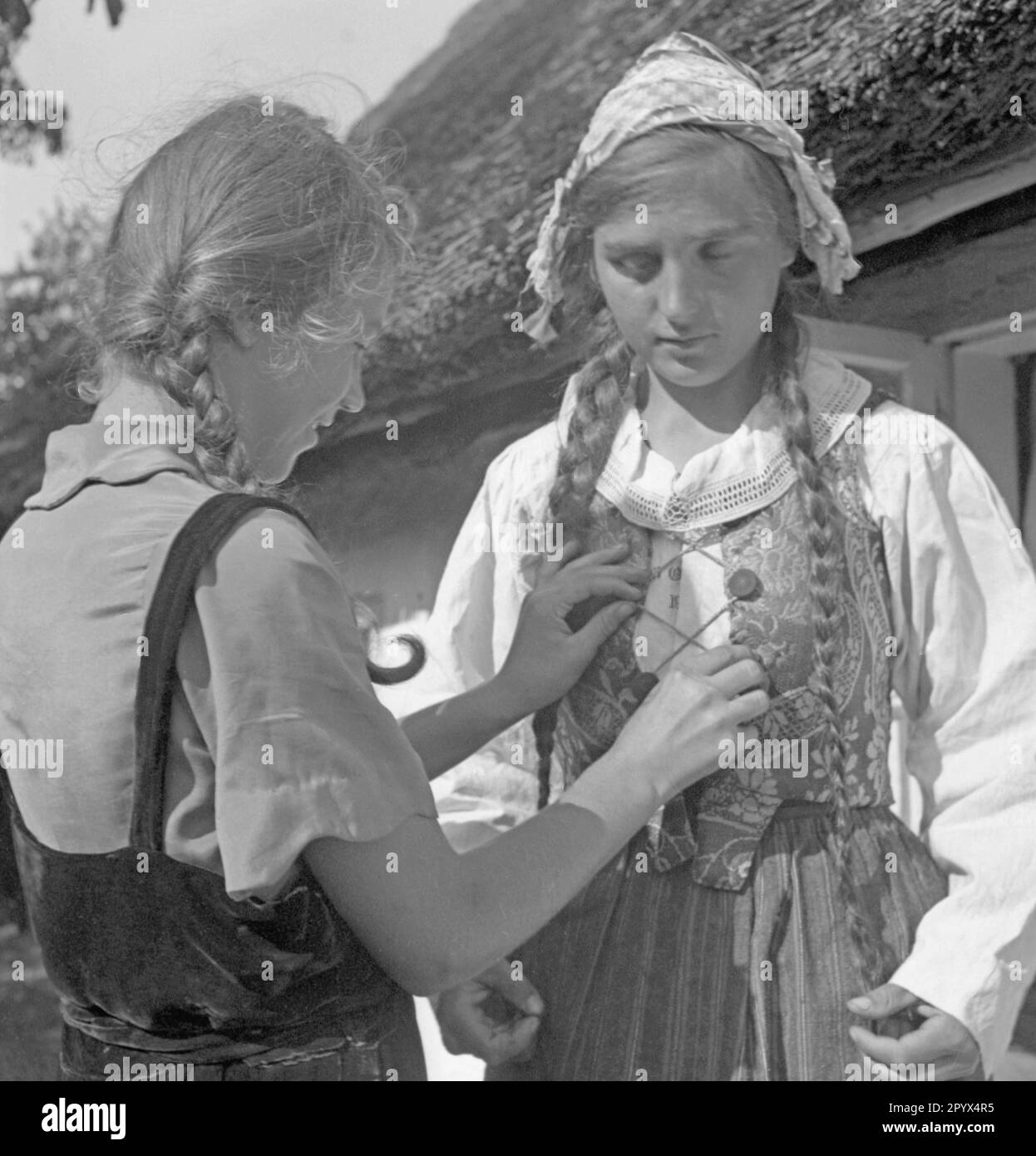 A girl buttons the bodice of a traditional dress of a friend Stock ...
