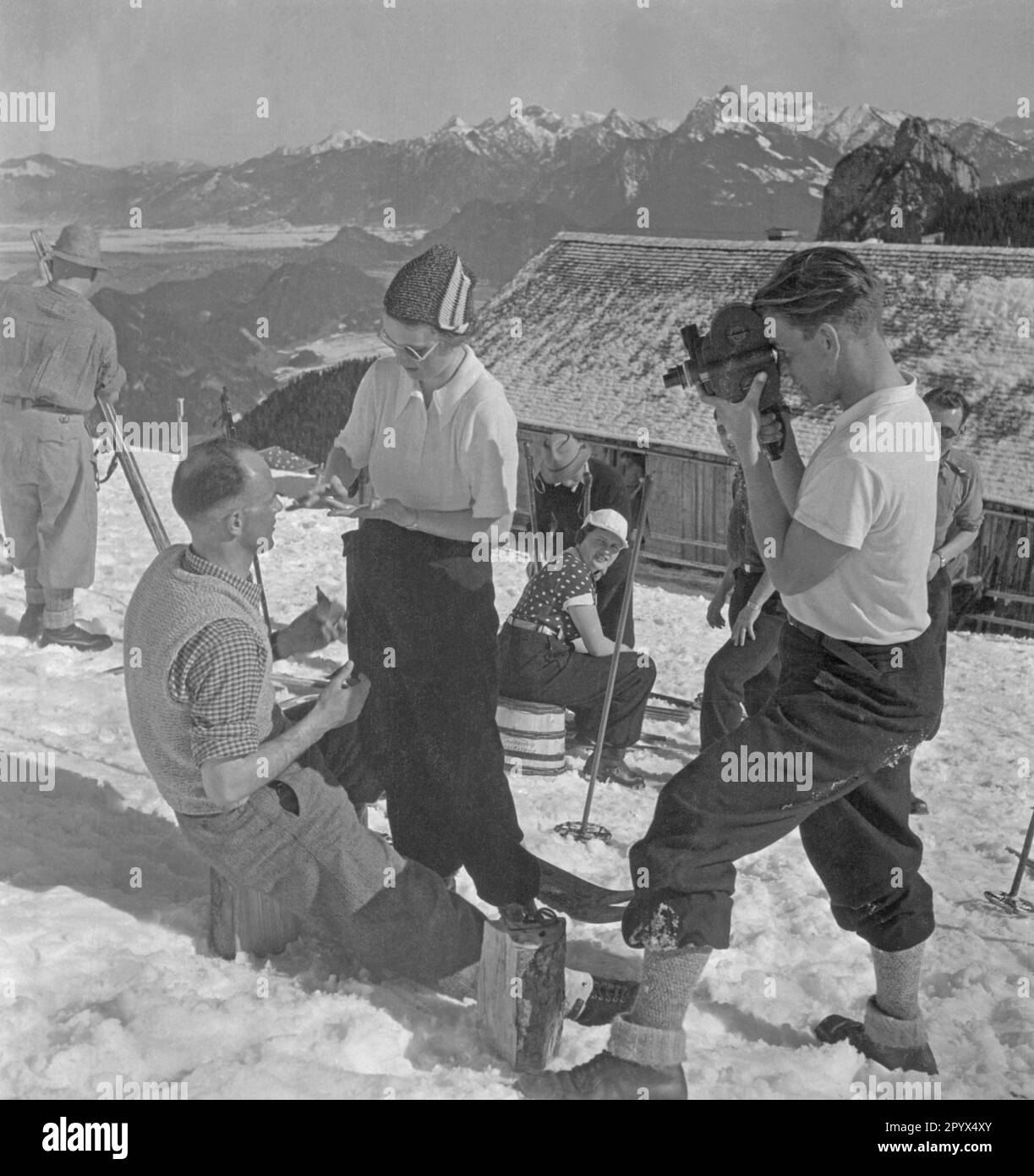 "A man films a couple on a high alpine pasture with a handheld camera ...