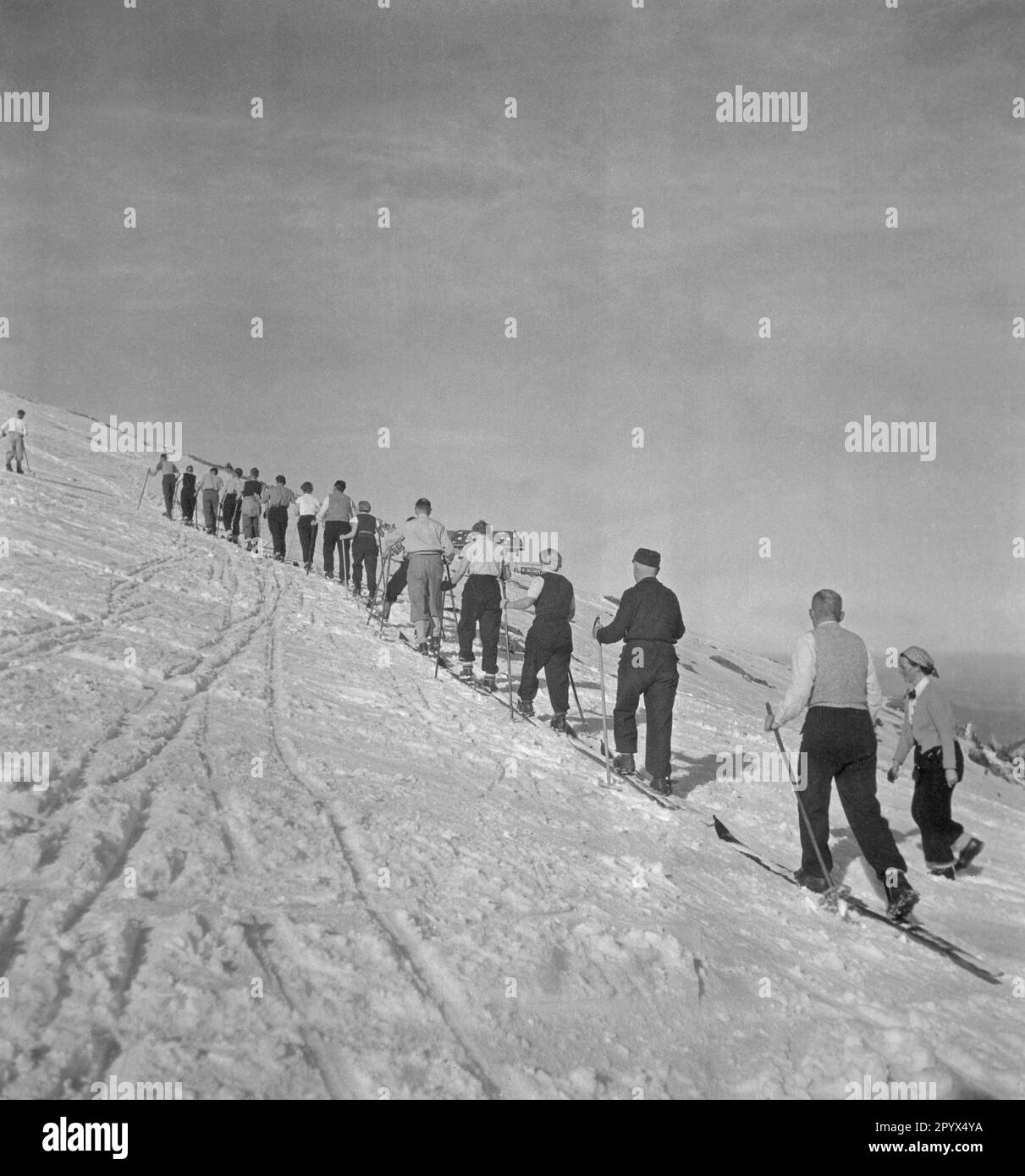 "View of a group of skiers ascending a high alpine pasture in a ...