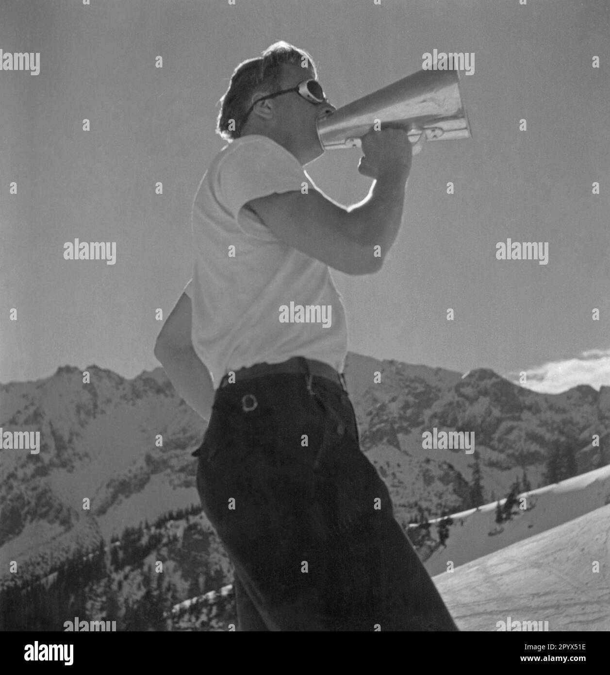 "A man calls through a mouthpiece made of sheet metal on a high alpine ...