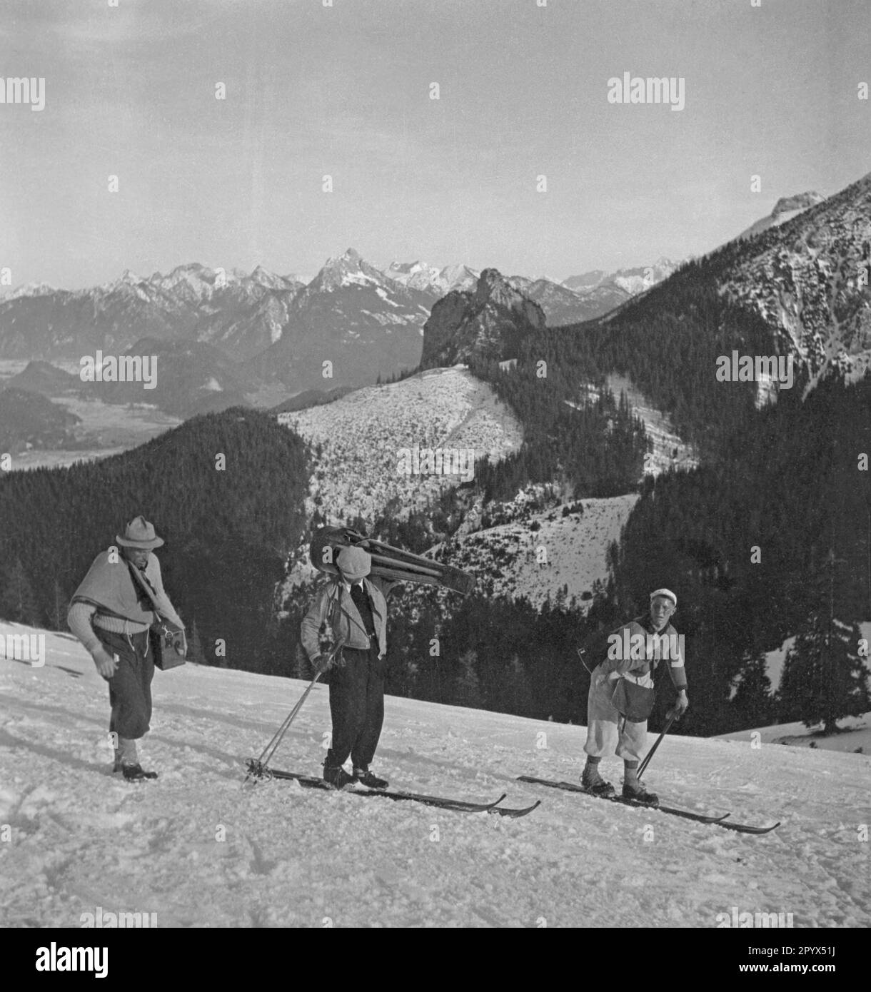 "View of a group of skiers ascending a high alpine pasture in a ...