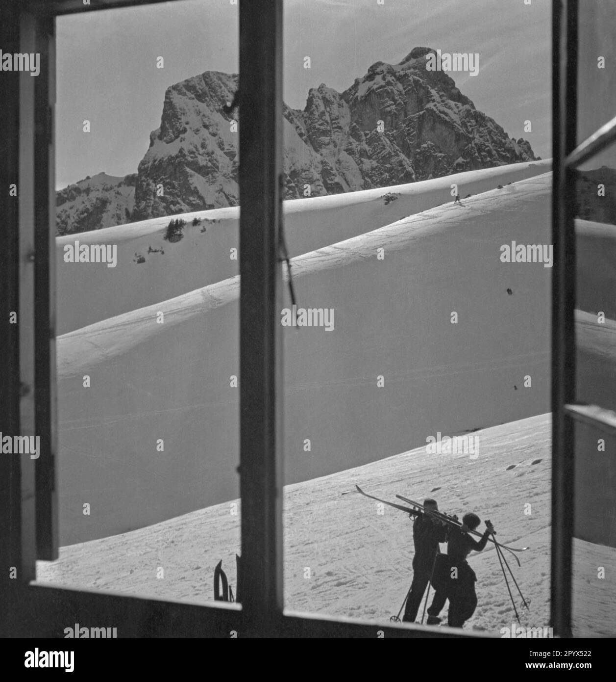 "Look from a window on two skiers in front of a hut. High alpine ...