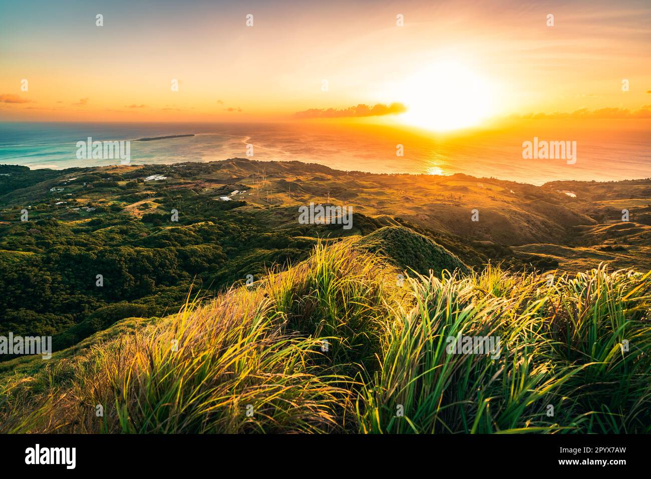A majestic sunrise over the hills and ocean below, with lush green ...