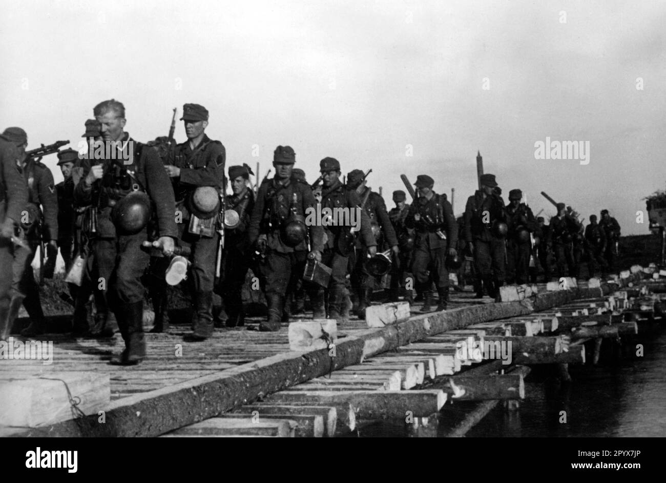 Mountain troops crossing a river on a bridge built by sappers during ...