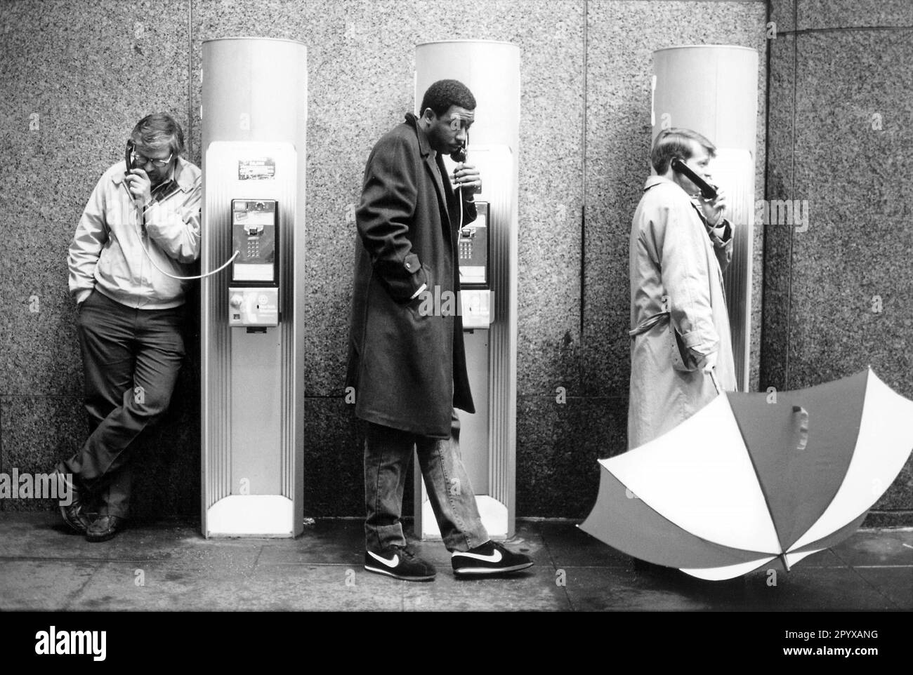 Three men make phone calls at public phone booths in New York ... Three men make phone calls at public phone booths in New York ...