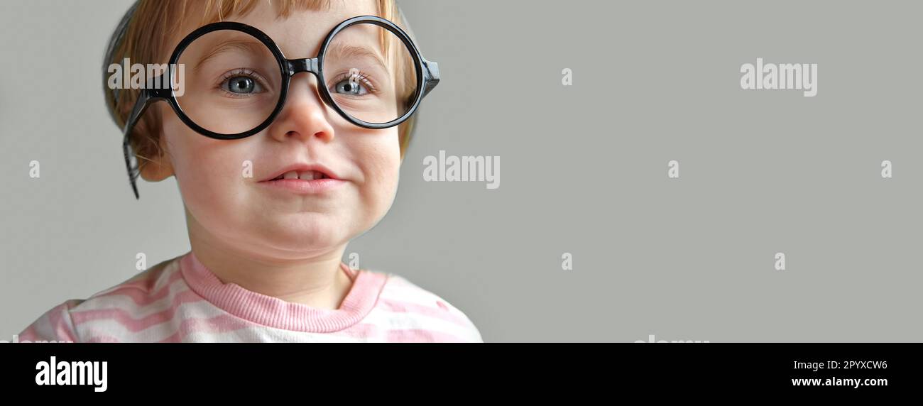 Funny child wearing round glasses on gray studio background. Little ...
