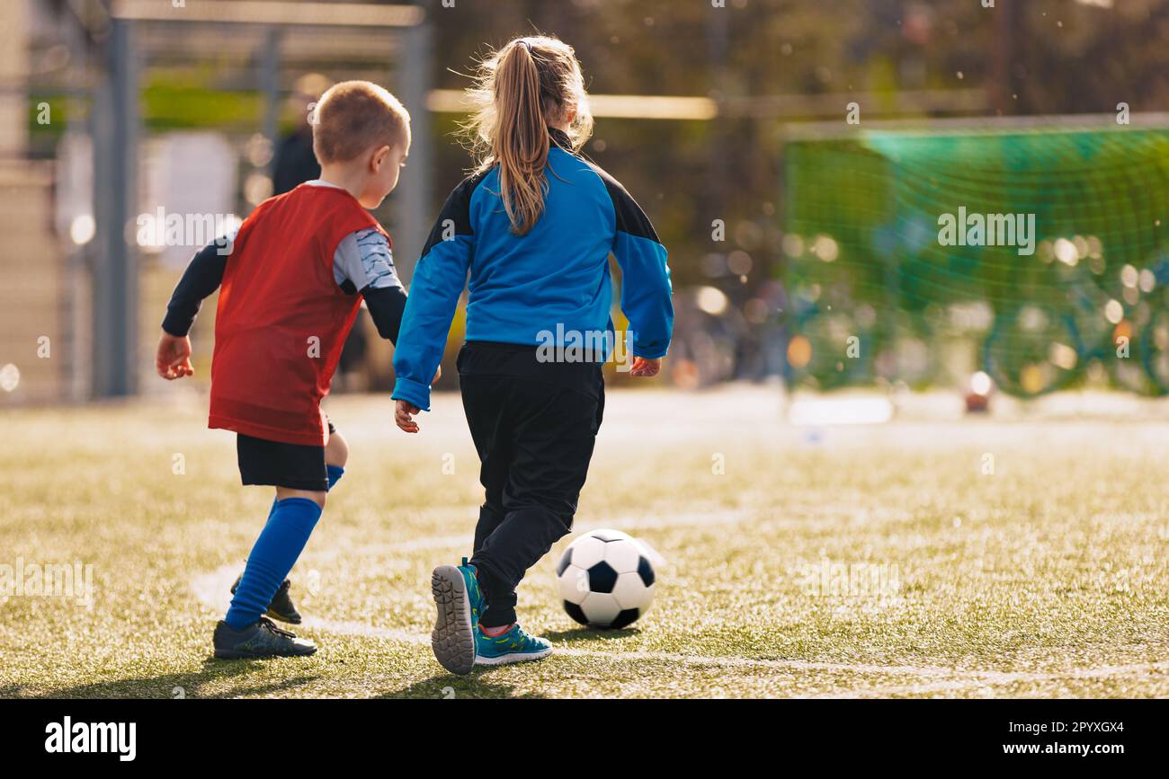 Little boy and girl running and kicking soccer ball. Football lesson ...