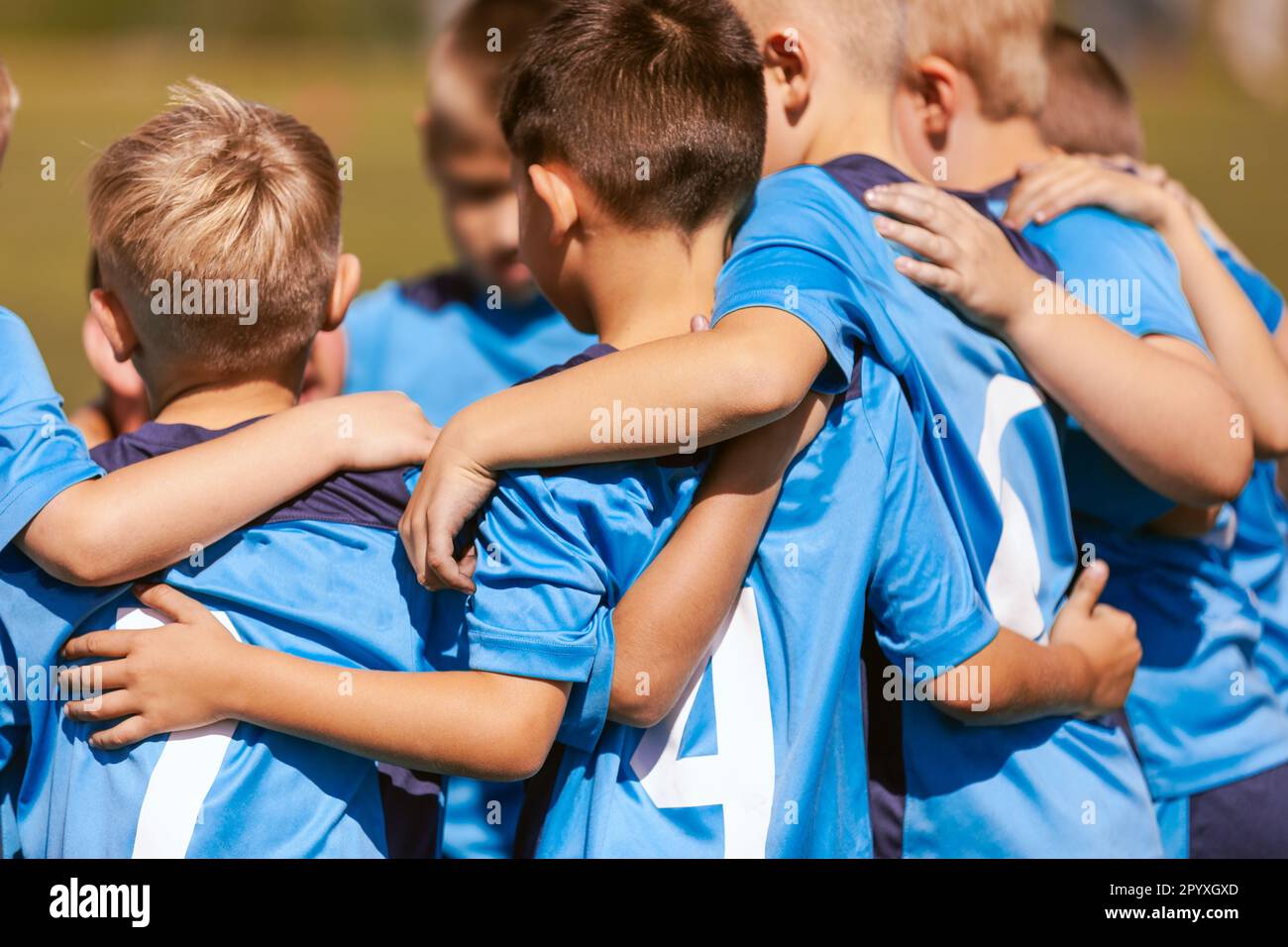 Motivated kids in soccer team cheering on court. Players huddling in a ...
