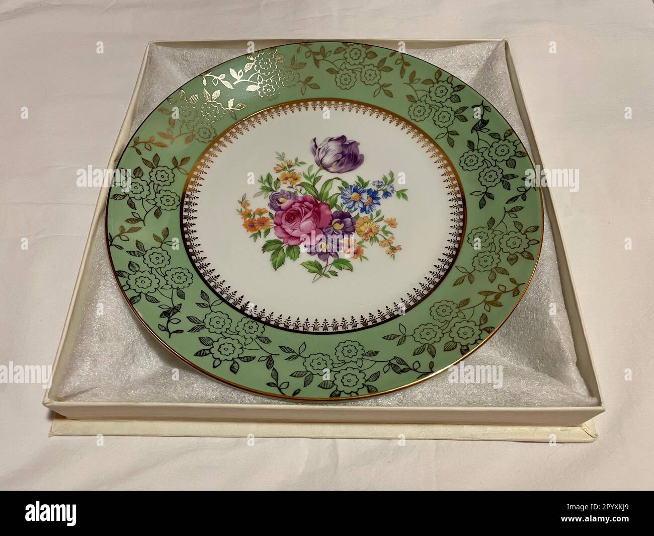 Antique plate with floral design and gilt green edges in box on white ...